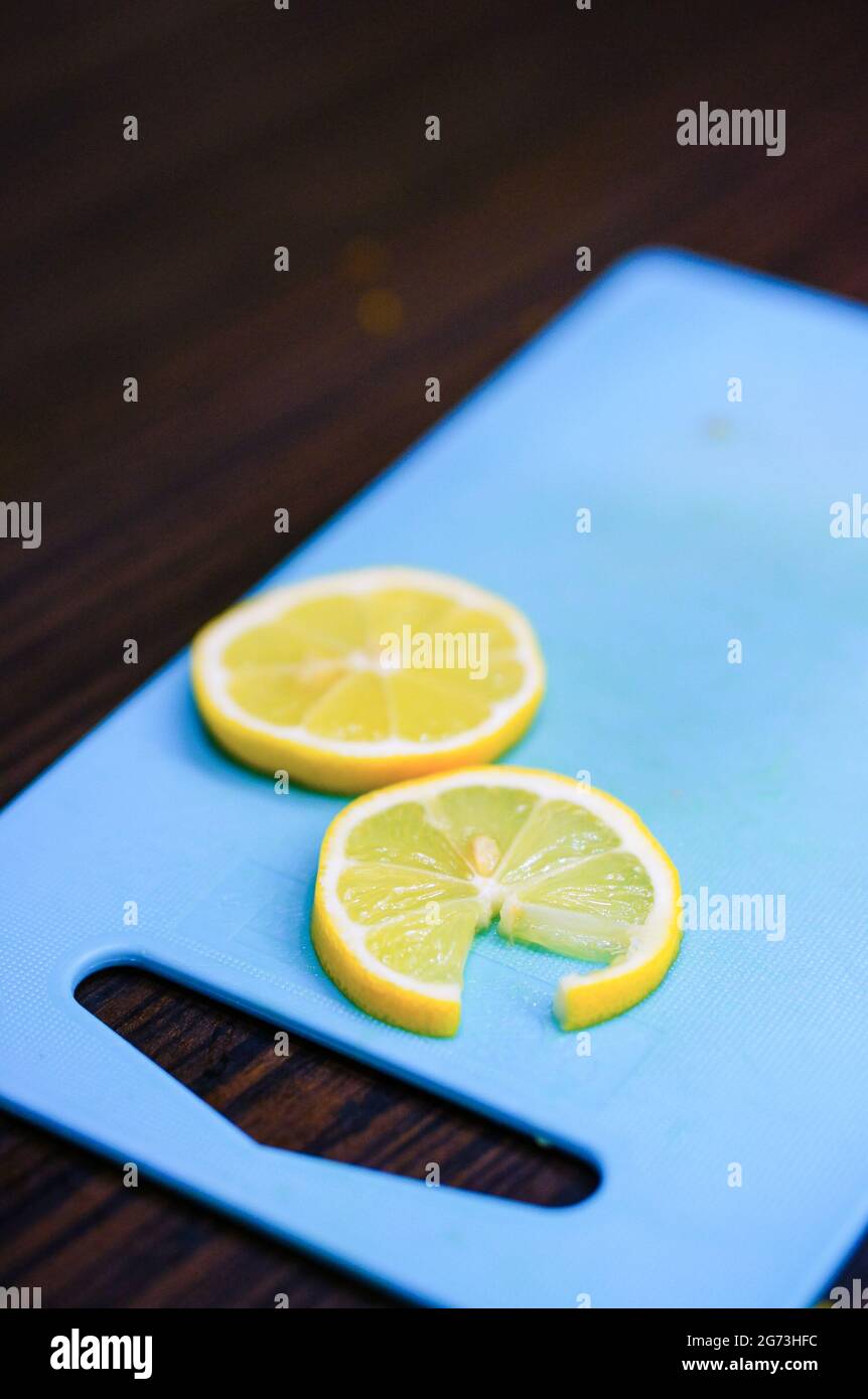 Vertical shot of two lemon pieces on a blue cutting board Stock Photo ...