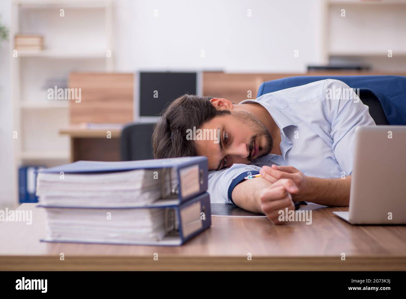 Young male drug addicted employee in the office Stock Photo - Alamy