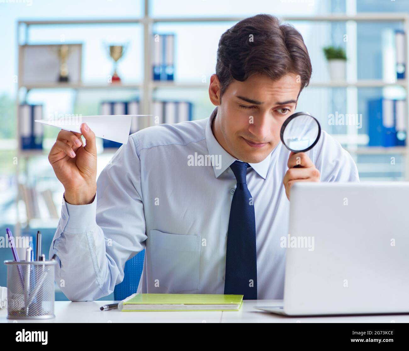 The businessman with magnifying glass and paper plane Stock Photo - Alamy