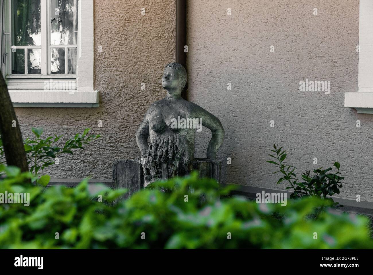 Old statue and green plants in front of a house Stock Photo - Alamy