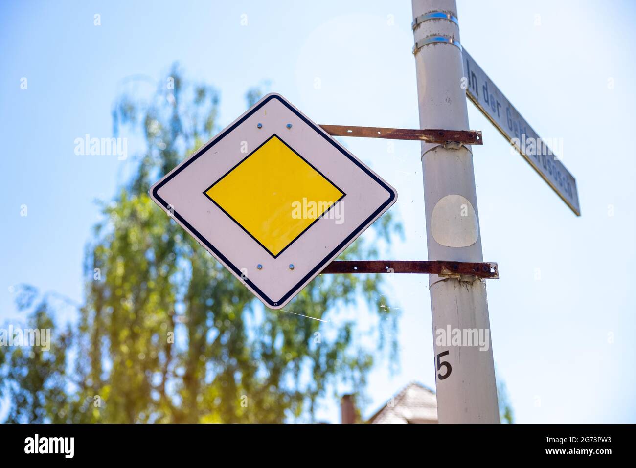 Closeup of the German right of way sign on a pole with sunlight shining ...