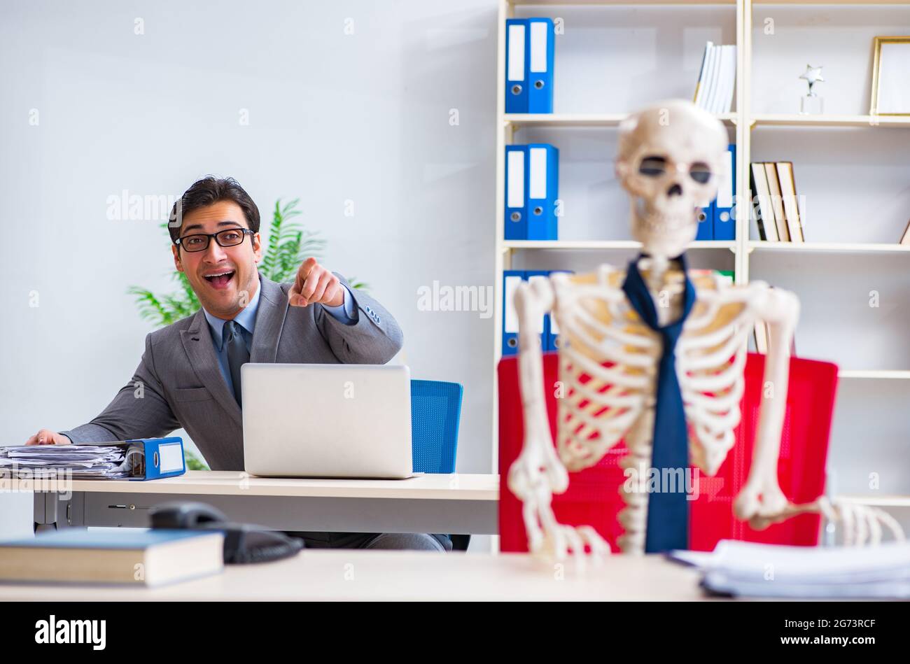 The businessman working with skeleton in office Stock Photo - Alamy