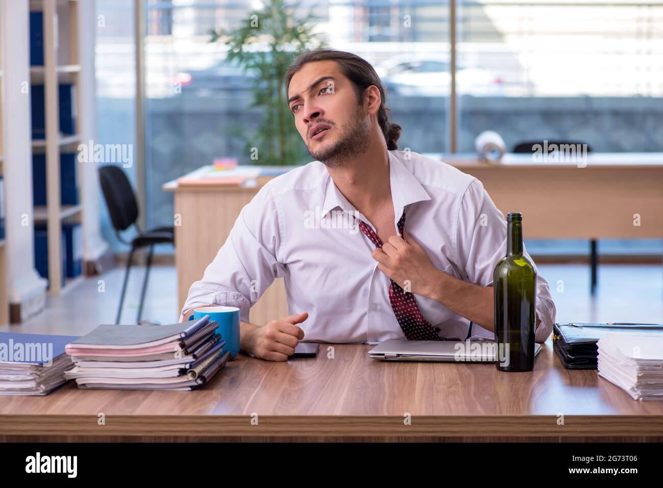 Young alcohol addicted employee working in the office Stock Photo - Alamy