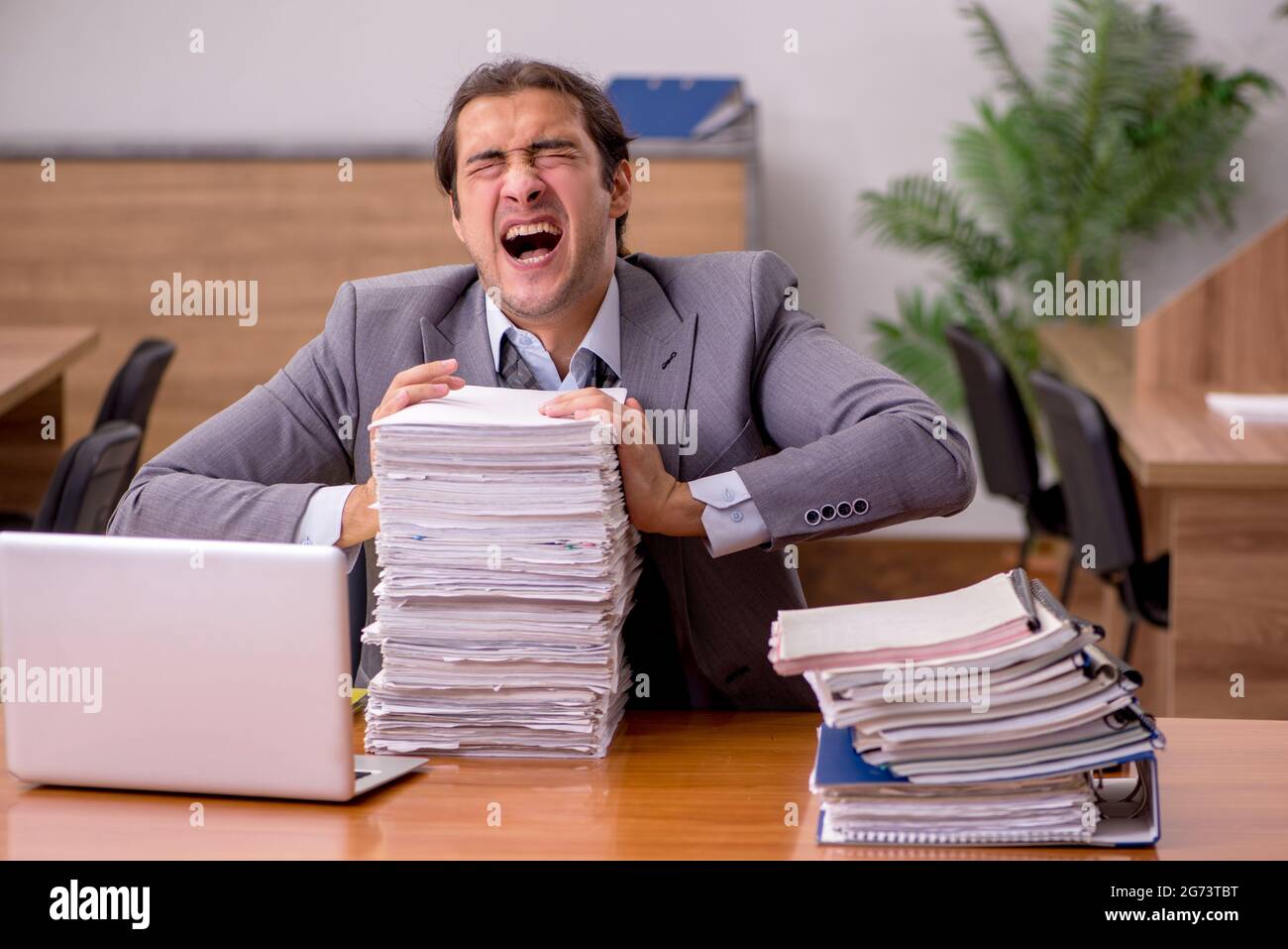 Young employee and too much work in the office Stock Photo - Alamy