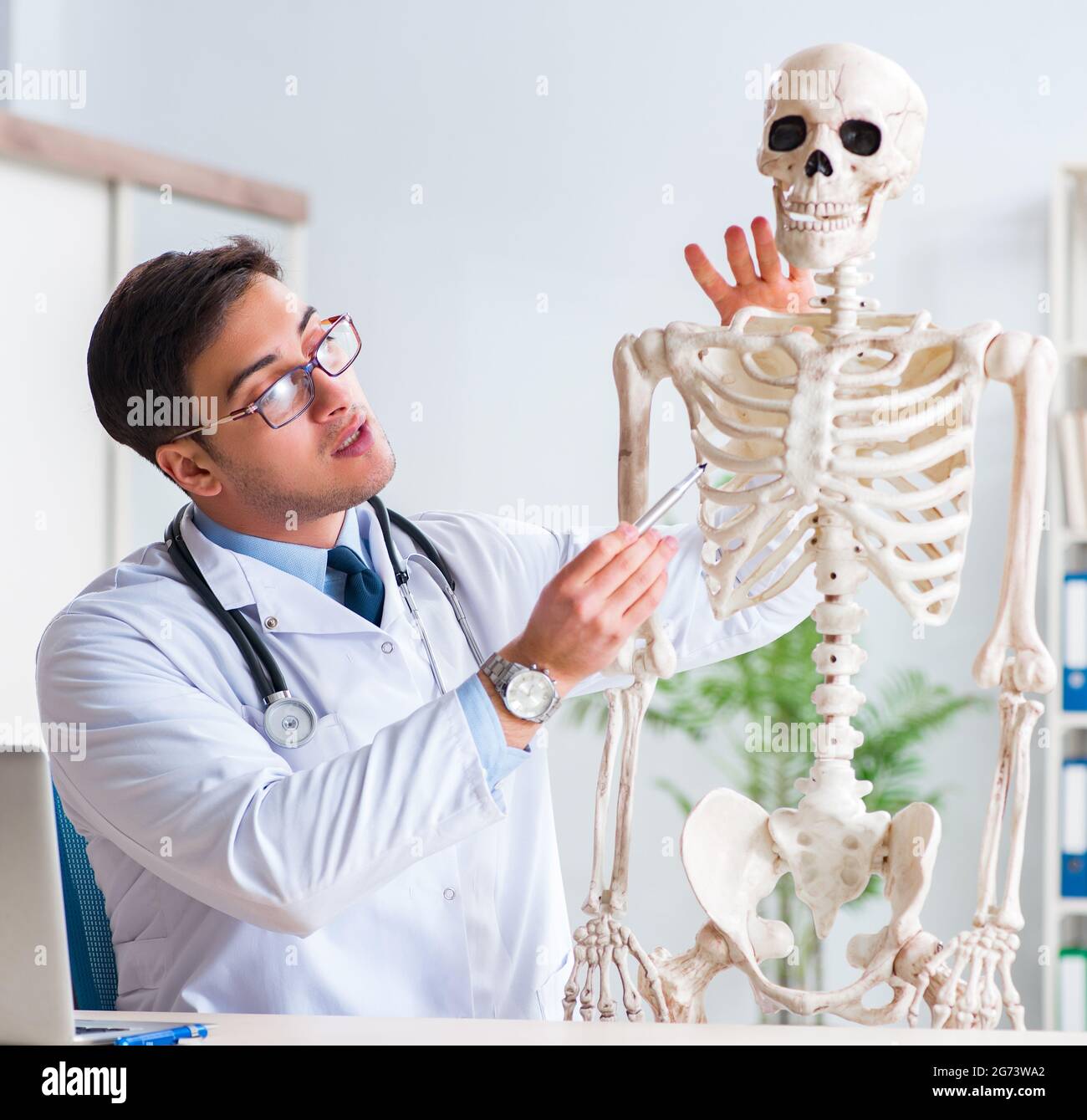 The yong male doctor with skeleton isolated on white Stock Photo - Alamy