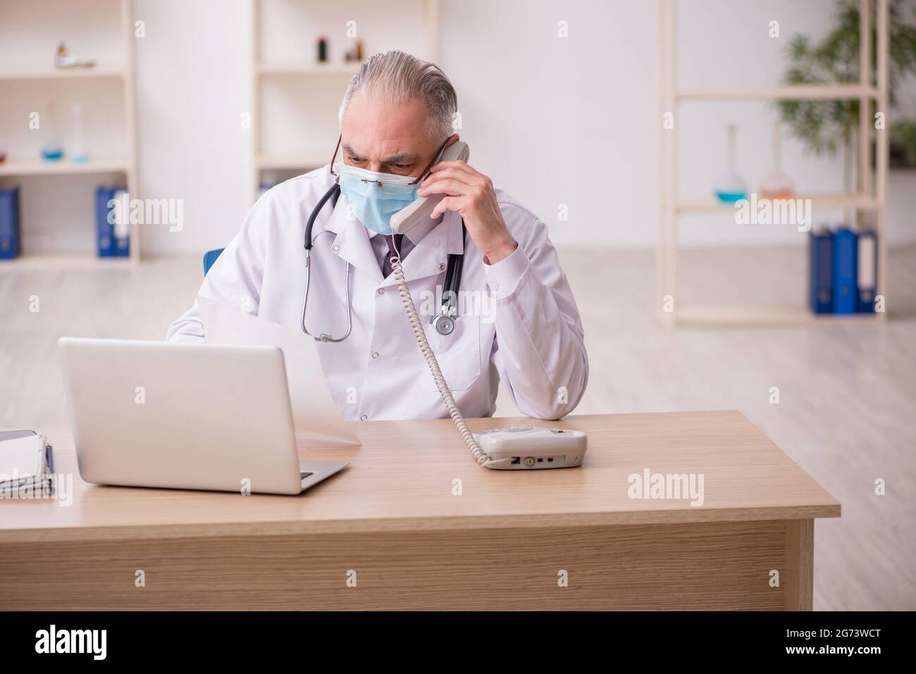 Old doctor working in the clinic during pandemic Stock Photo - Alamy