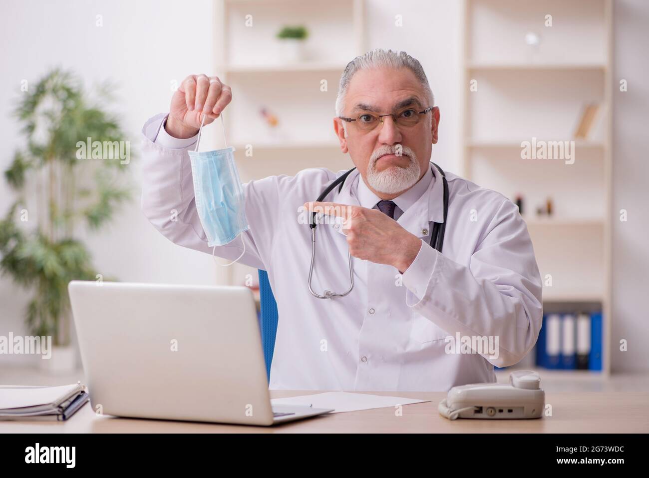 Old doctor working in the clinic during pandemic Stock Photo - Alamy