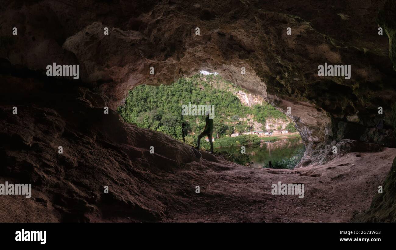 A Silhouette of a Hispanic man standing inside a dark cave enjoying ...