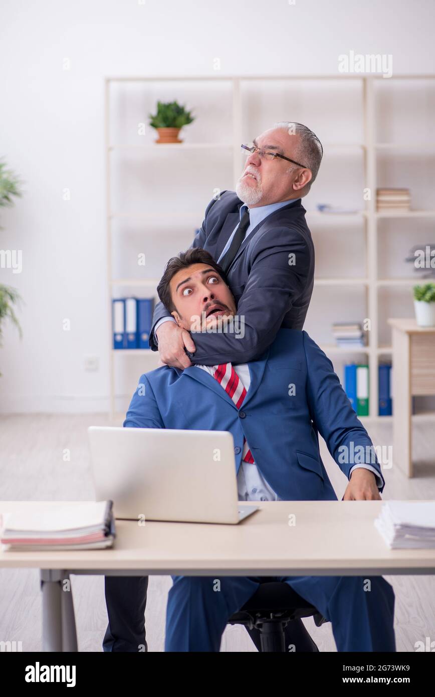 Old boss and young employee in bullying concept Stock Photo - Alamy