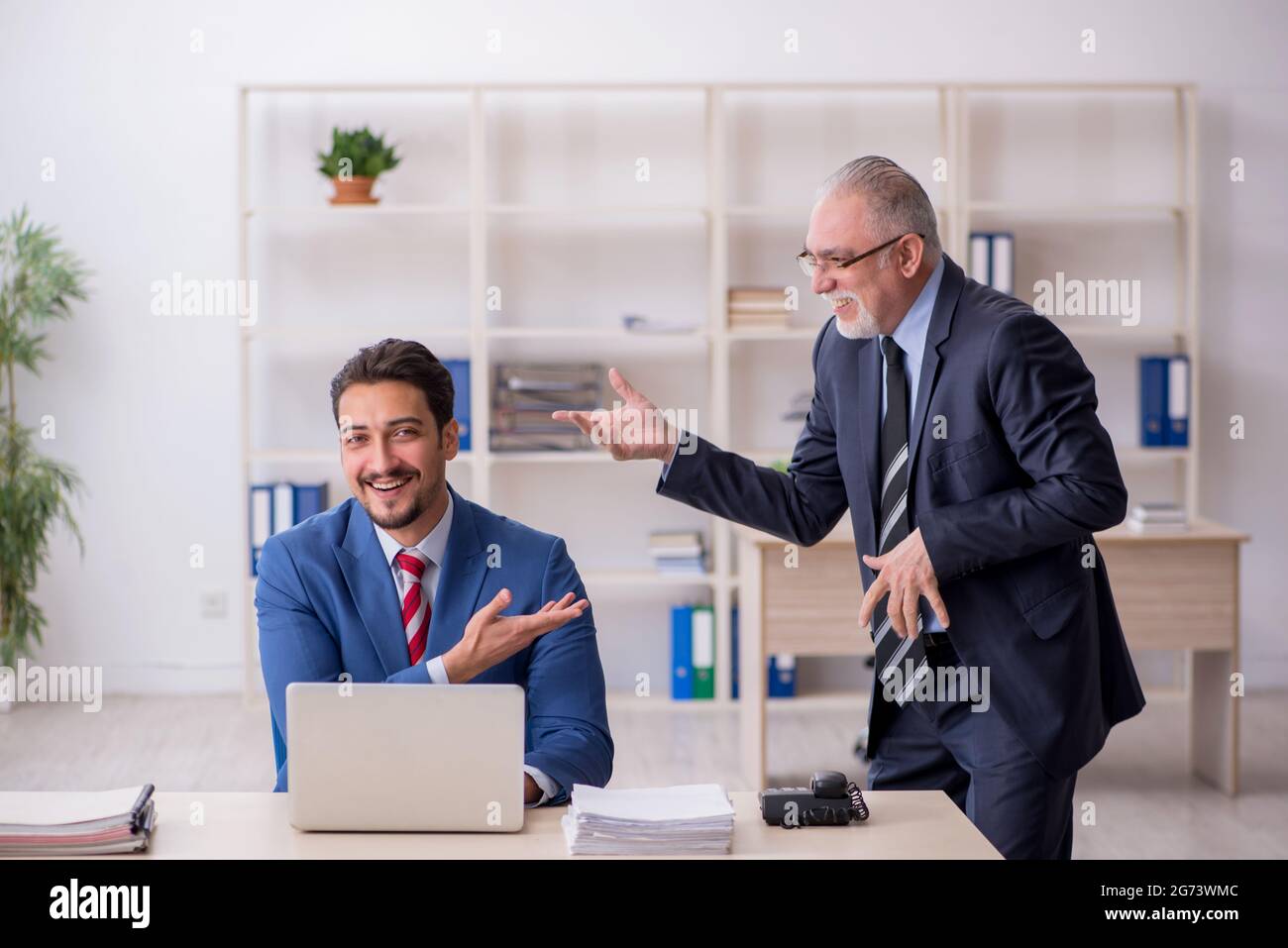Old boss and young employee in bullying concept Stock Photo - Alamy