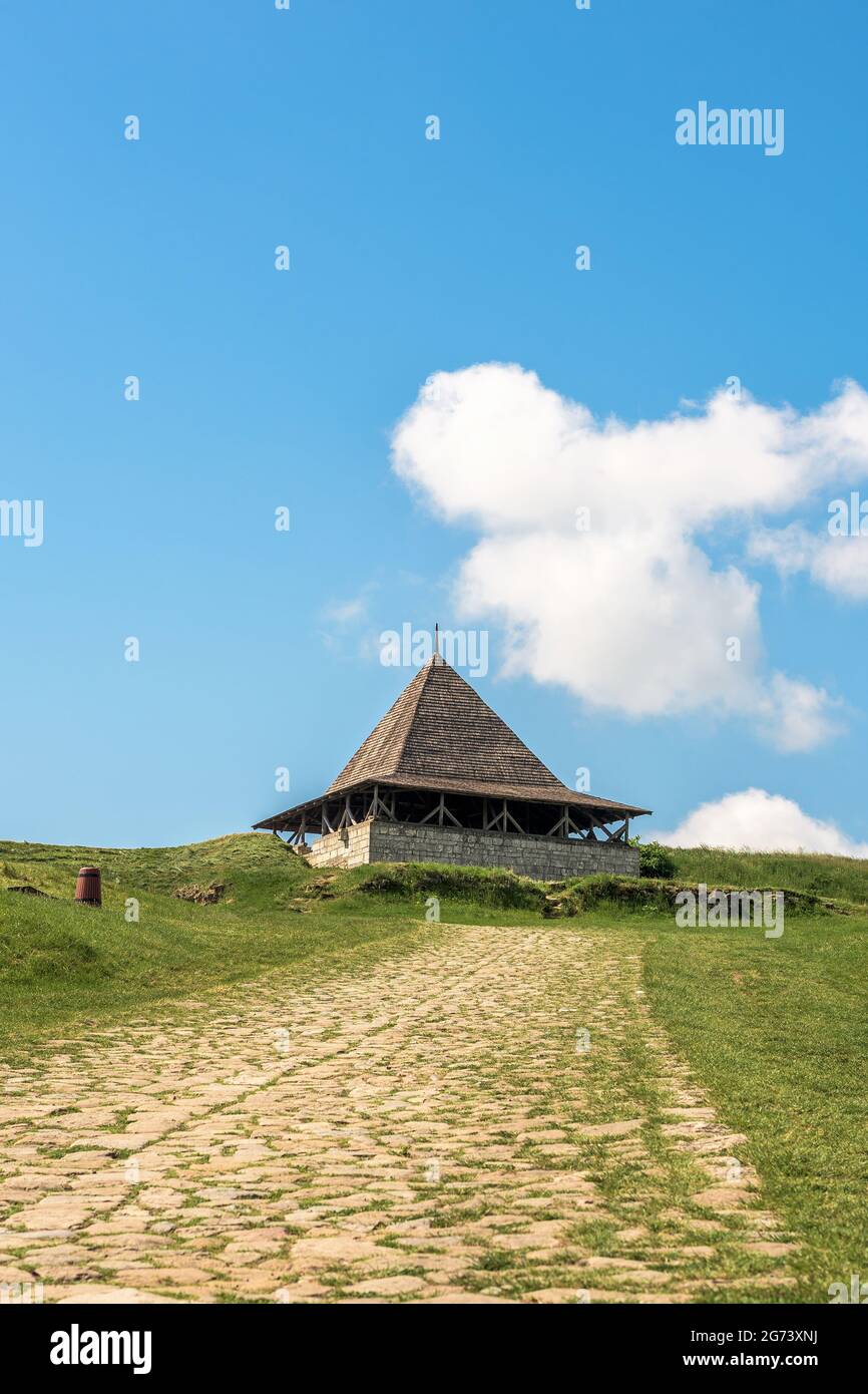A small building with a sharp, dark brown roof in the green field ...