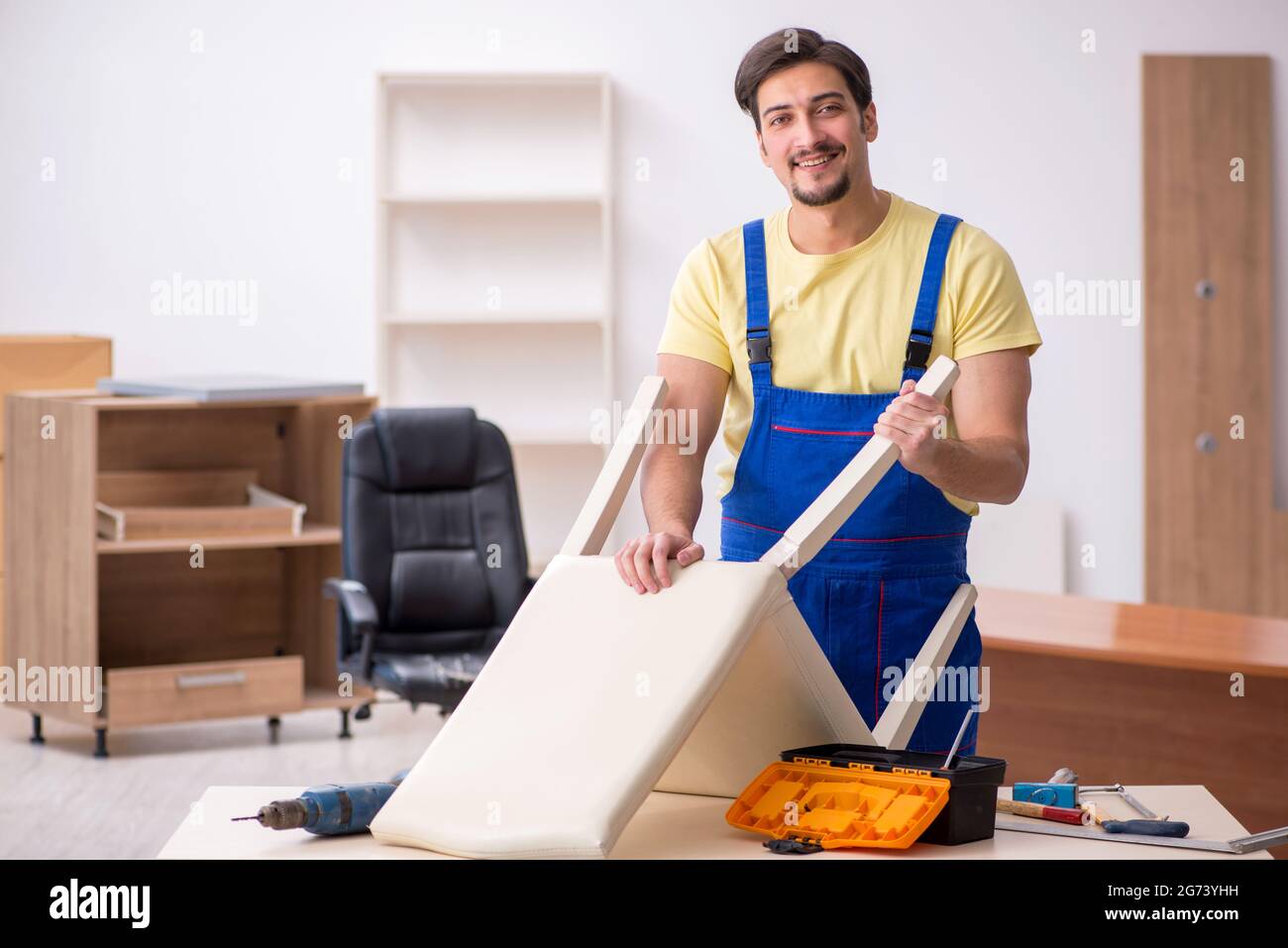 Young carpenter repairing chair in the office Stock Photo - Alamy