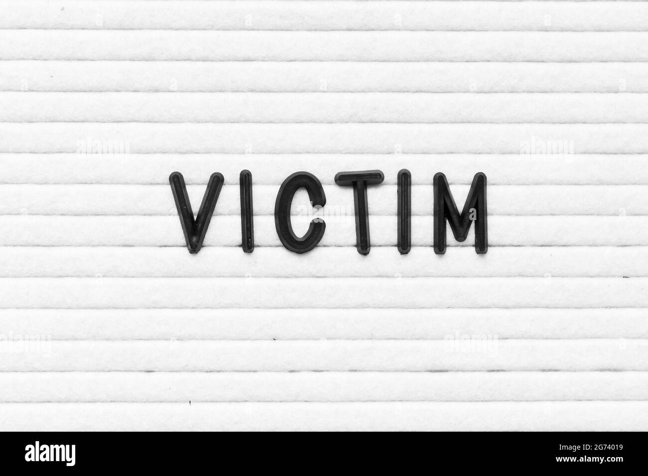 Black color letter in word victim on white felt board background Stock ...