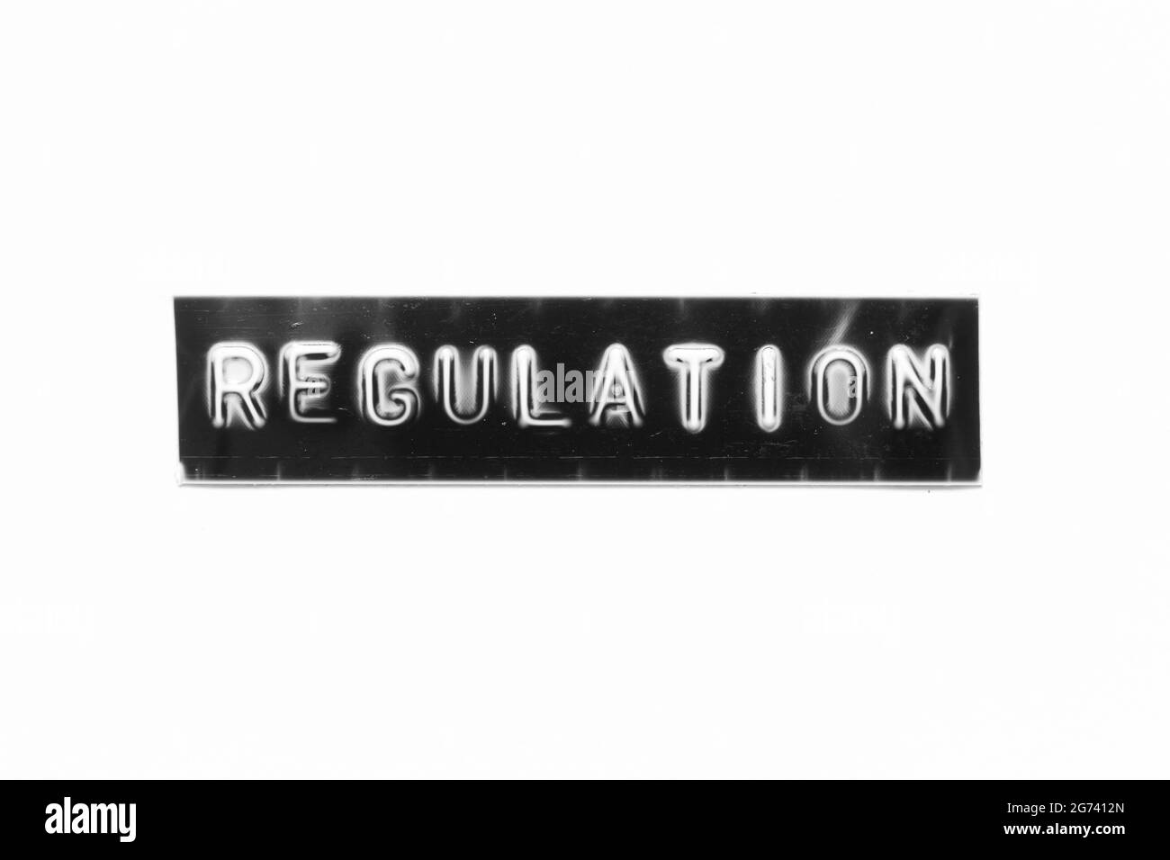 Embossed letter with word regulation in black banner on white paper ...
