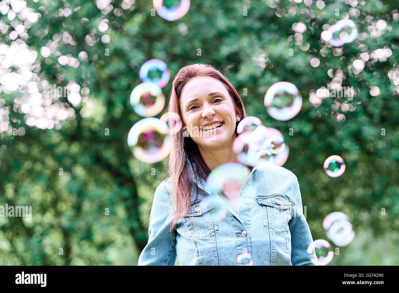 35 year old millennial woman surrounded by soap bubbles in summer or ...