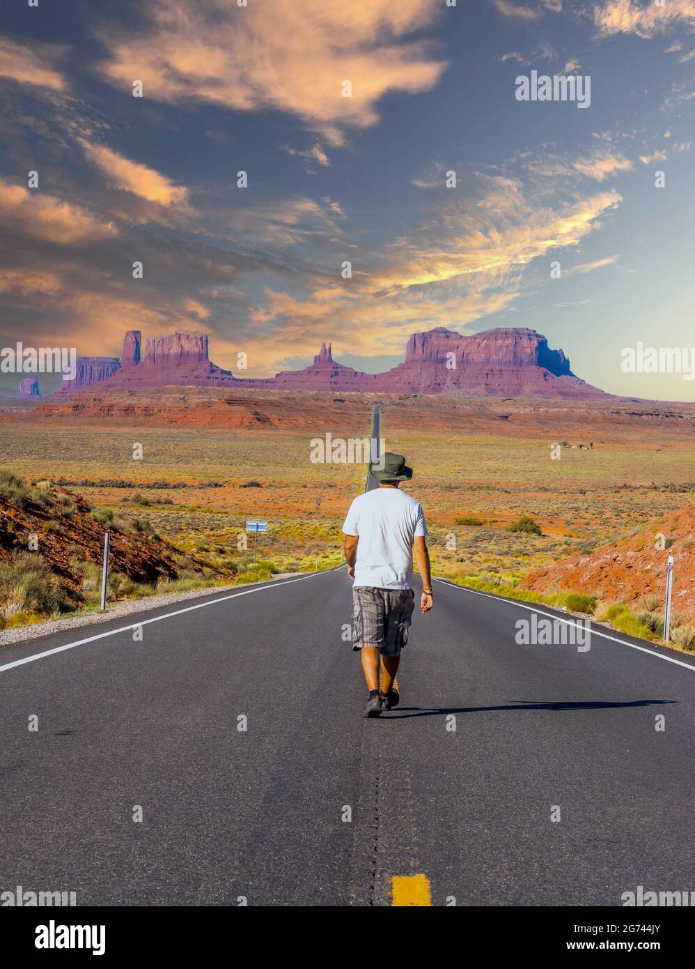 A vertical shot of a young man walking on the road to Monument Valley ...