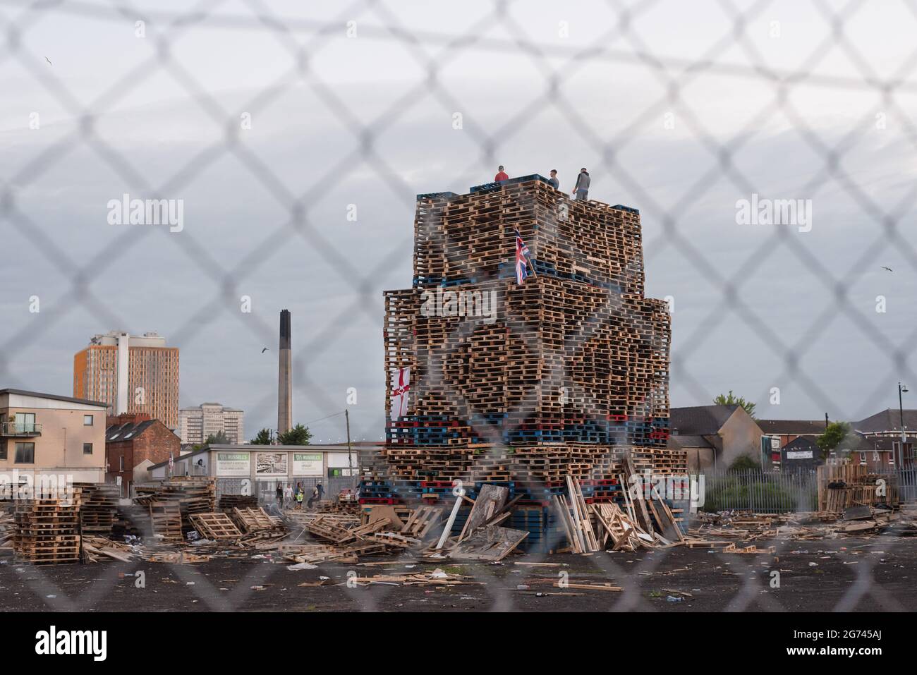 Through a chain link fence, young men seen completing the construction ...