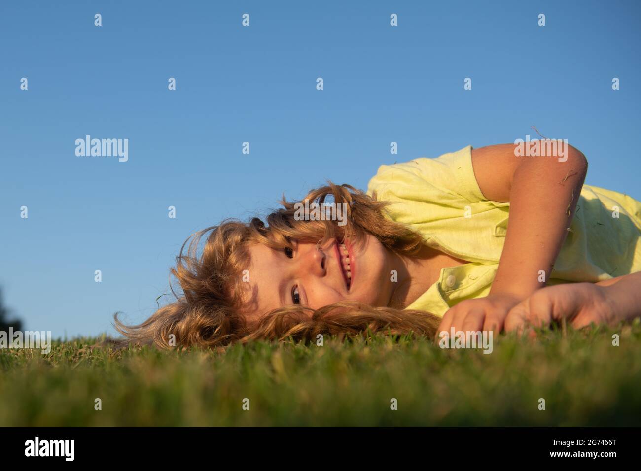 Portrait of a happy smiling child boy playing on grass field outdoor ...