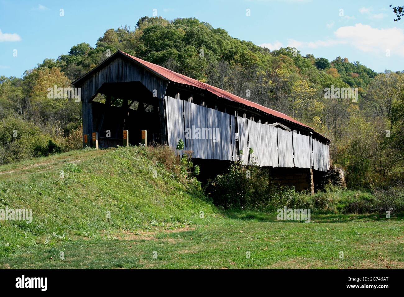 A covered bridge with rusty walls and trees on the background Stock ...