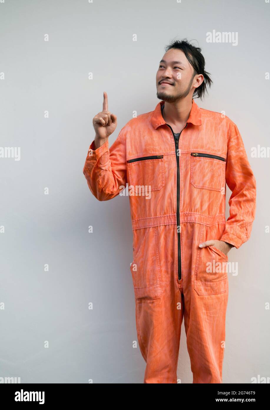 The chief mechanic in an orange uniform pointing one finger in upward ...
