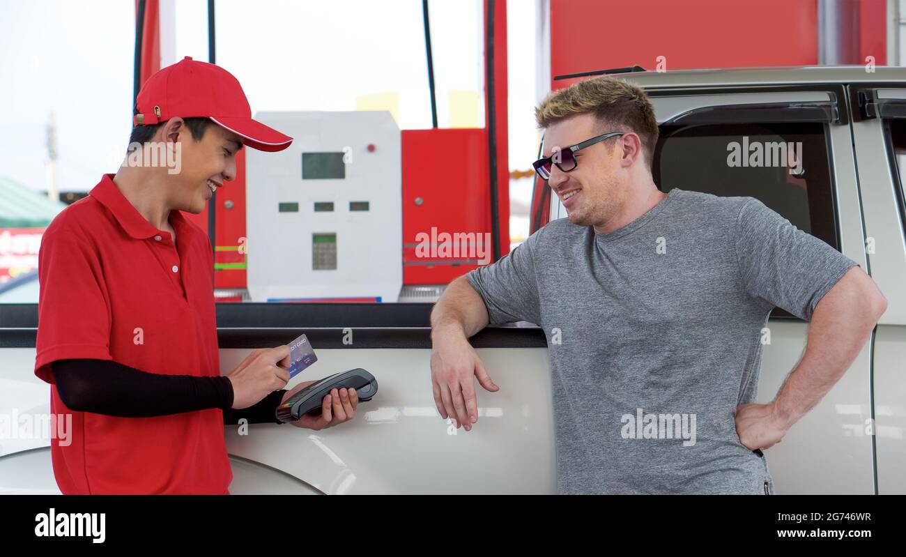 Gas station worker in red uniform stand smiling, swipe mockup credit ...