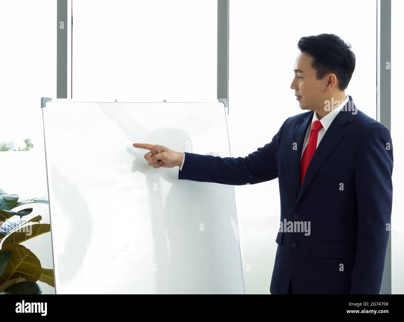 Asian businessman in suit pointing finger at white board. Training and ...
