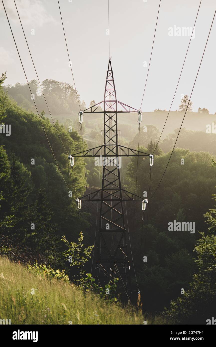 A vertical shot of electric power lines with insulators on a hill Stock ...