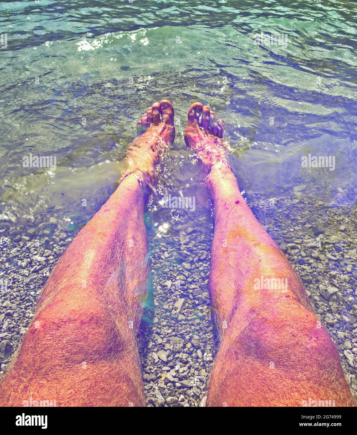 Two male legs on the sea water background. Sun rays flare. Abstract ...