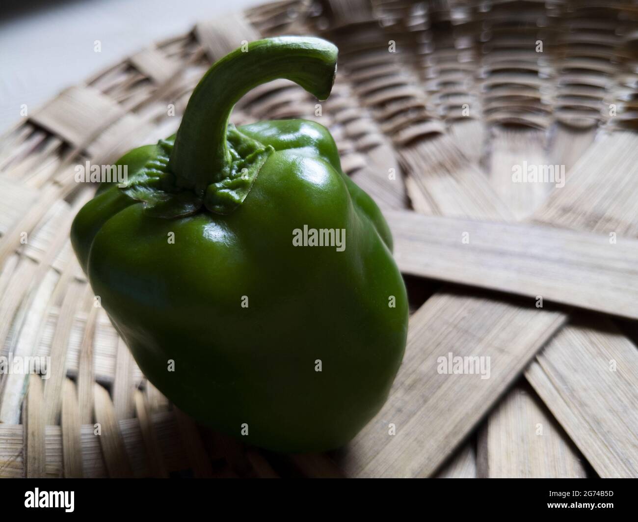 A top view of one green bell pepper in a straw plate Stock Photo - Alamy