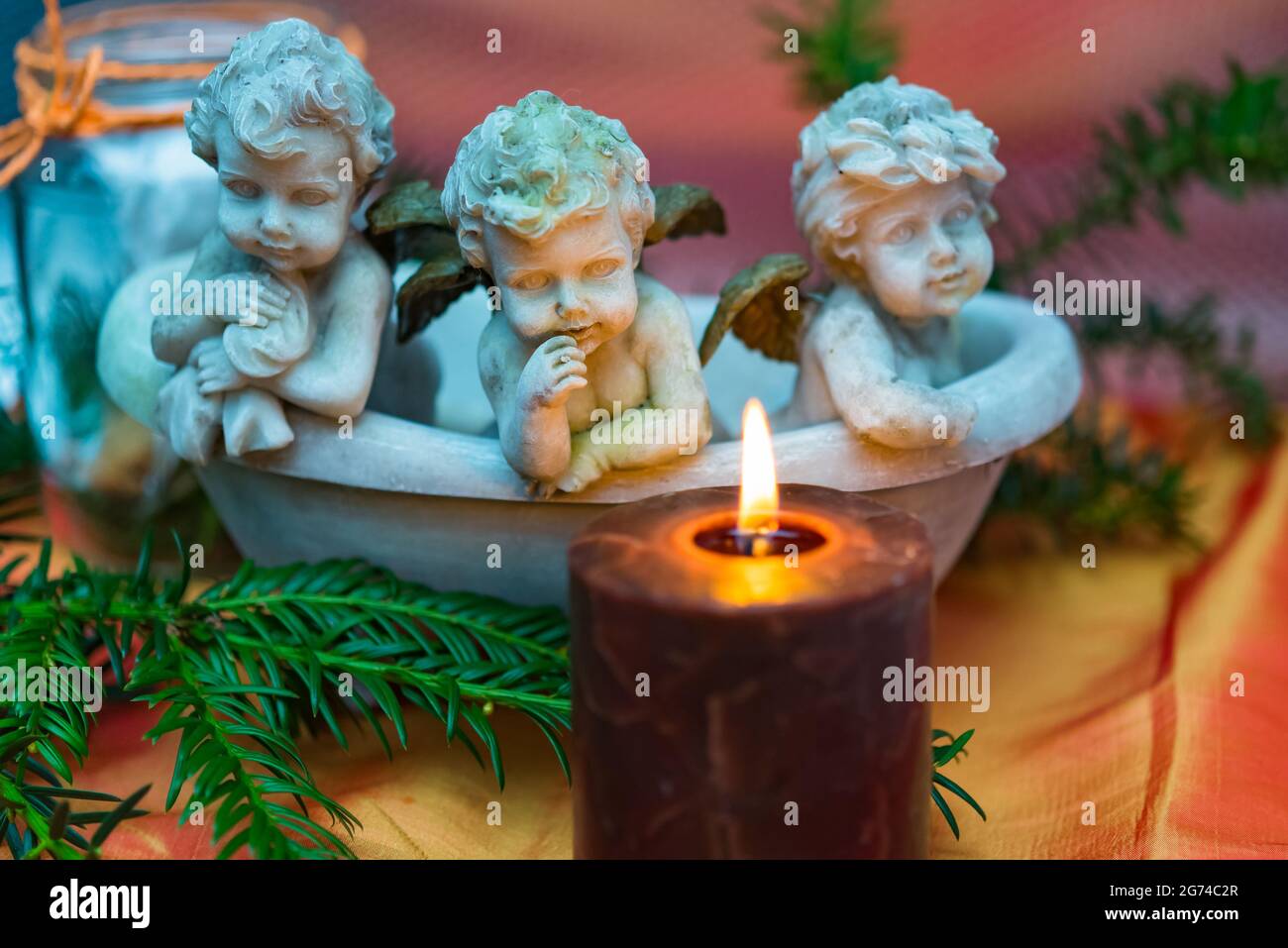 A closeup of small angel statues and a candle for a Christmas ...
