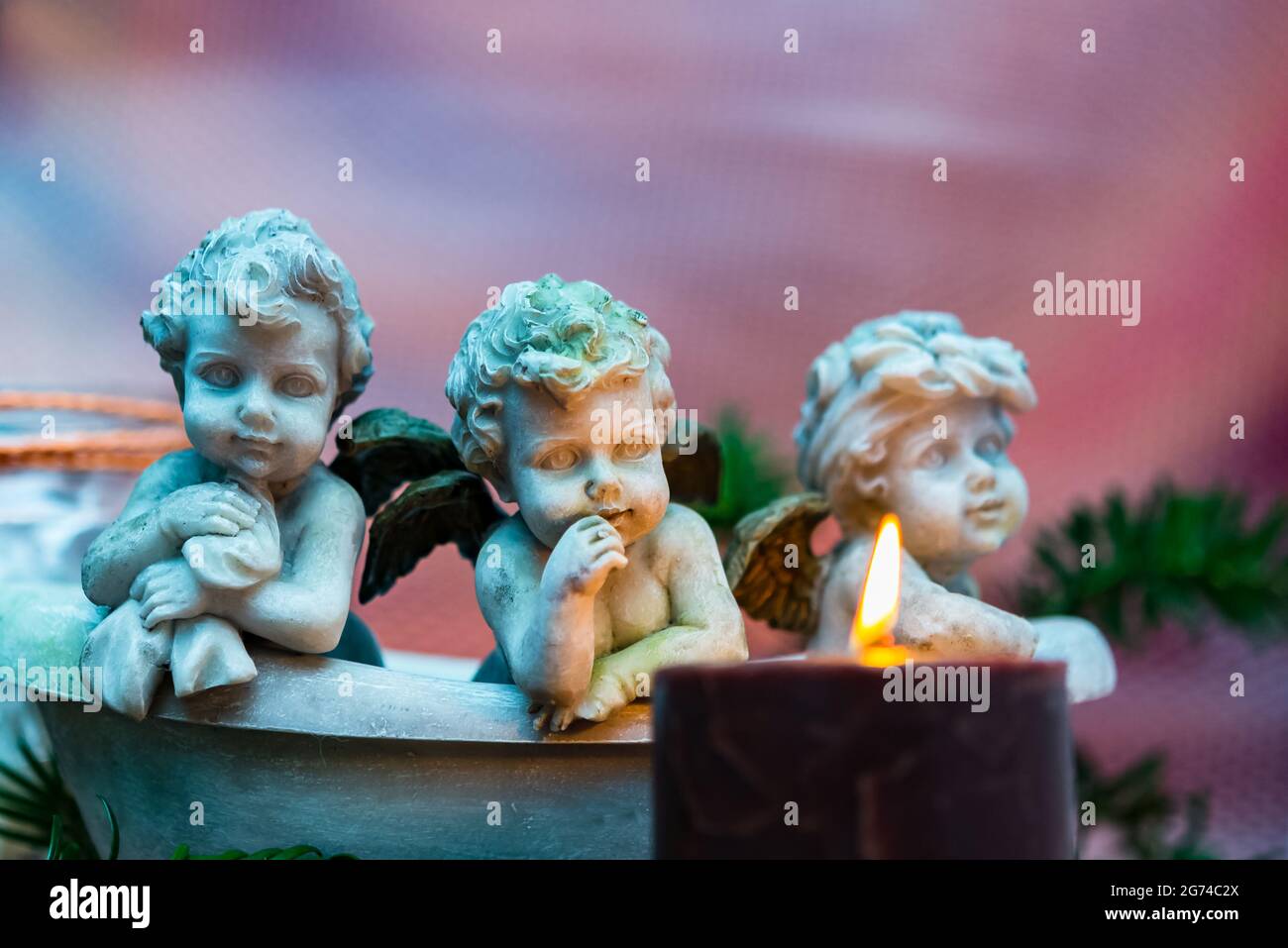 A closeup of small angel statues and a candle for a Christmas ...