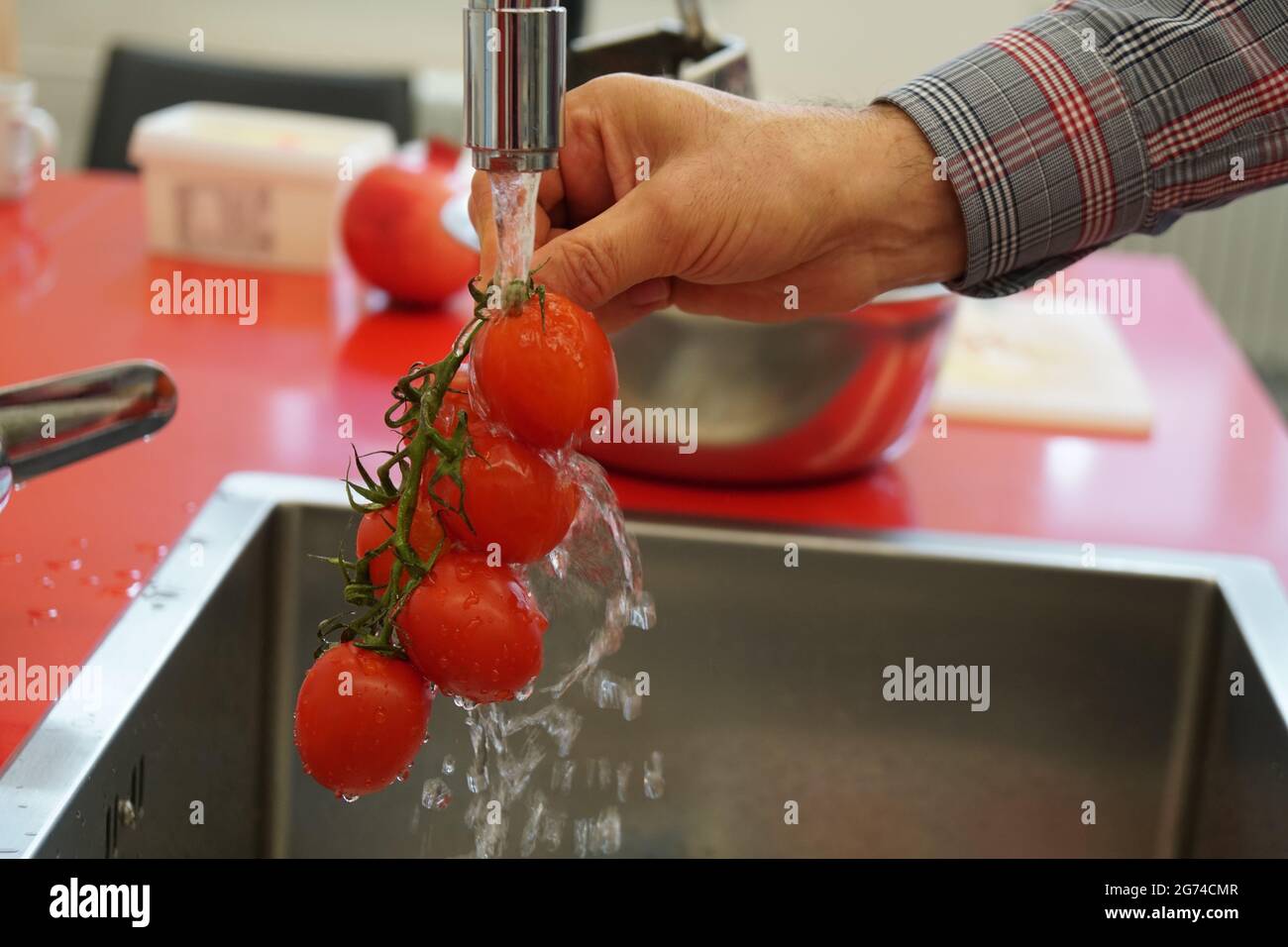 A closeup of a hand washing cherry tomatoes under the tap in the kitchen Stock Photo - Alamy