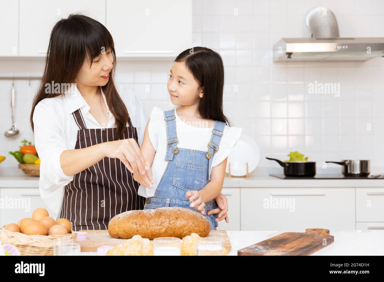 Mother and her child girl cooking food in home kitchen. Kid baking home ...