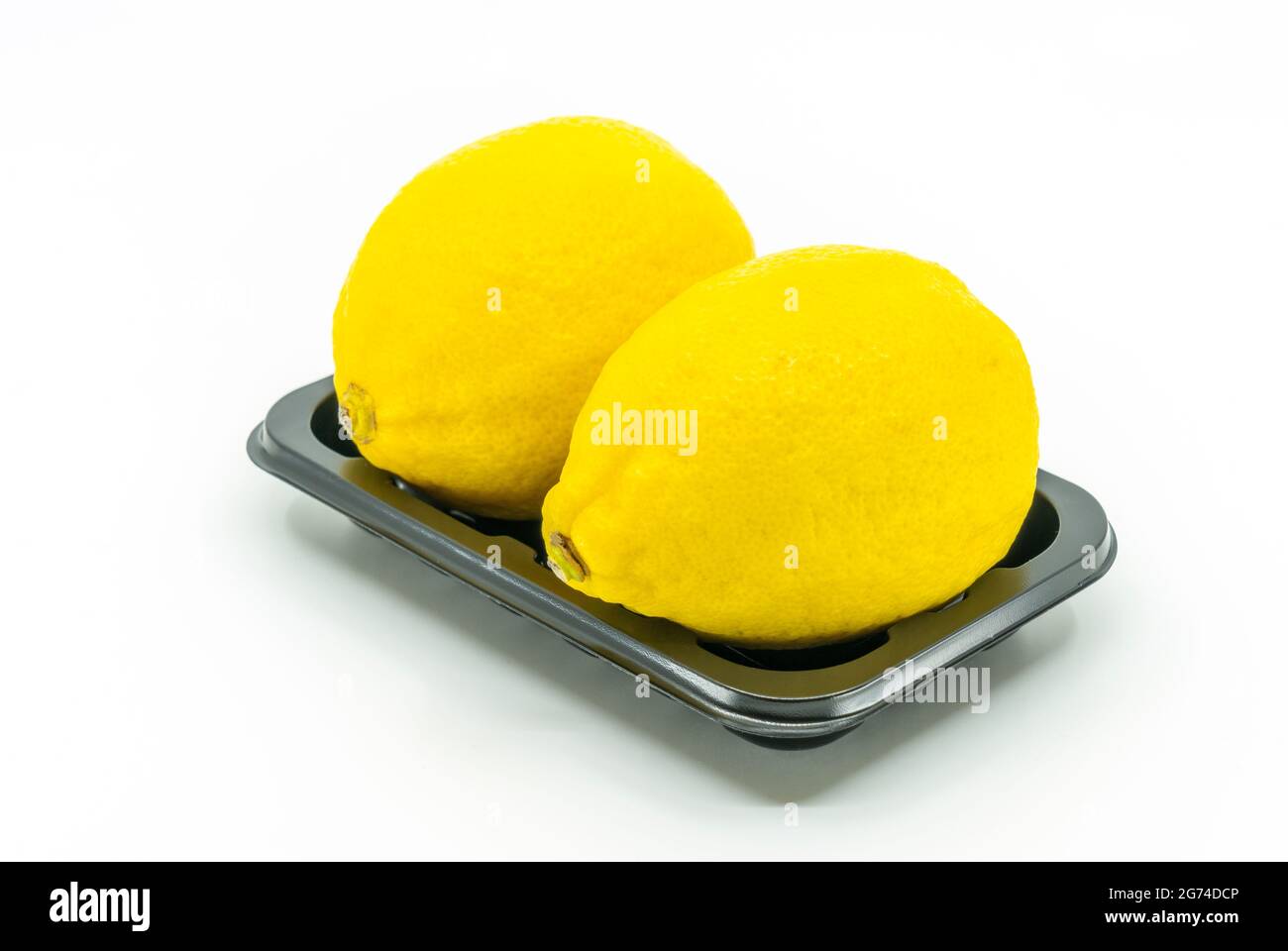 Fresh organic yellow lime in black tray, Isolated image on white background, two yellow limes in ...