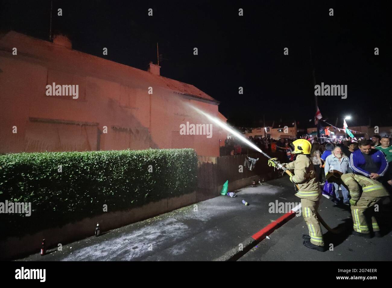 Fire fighters dampen down nearby properties as the huge bonfire in the ...