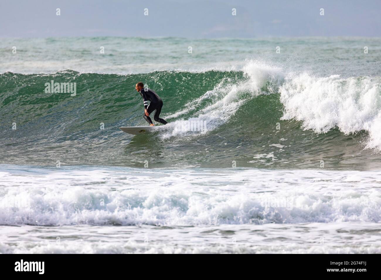Australian male surfer in wetsuit rides his surfboard on big surf at ...