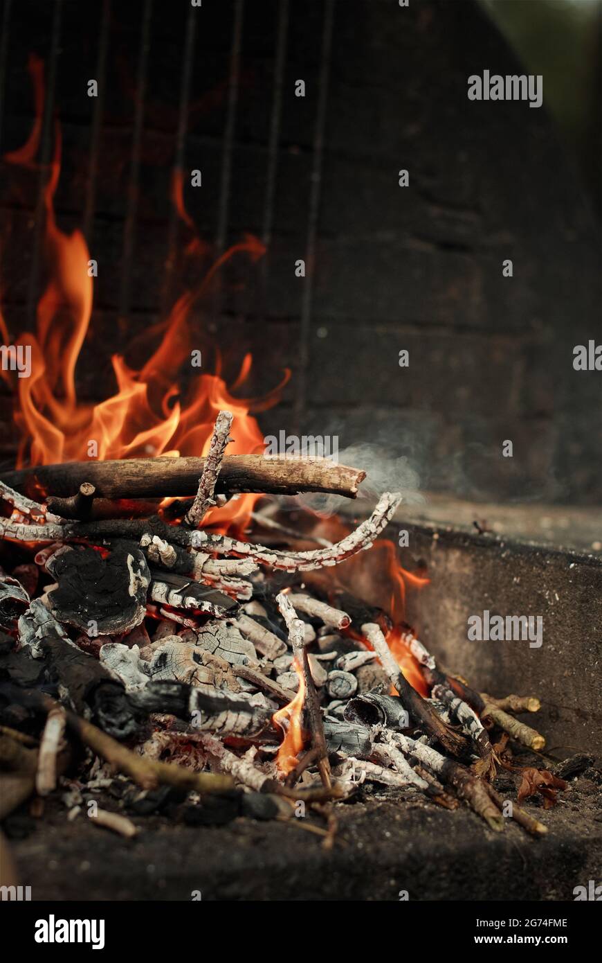 A vertical closeup of flames and charcoal that is burned to make a ...
