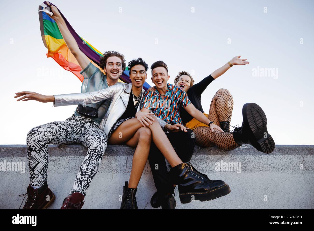 Young queer people celebrating gay pride. Group of four friends holding ...
