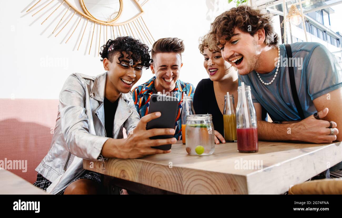 Four young people video calling their friends during lunch. Group of ...