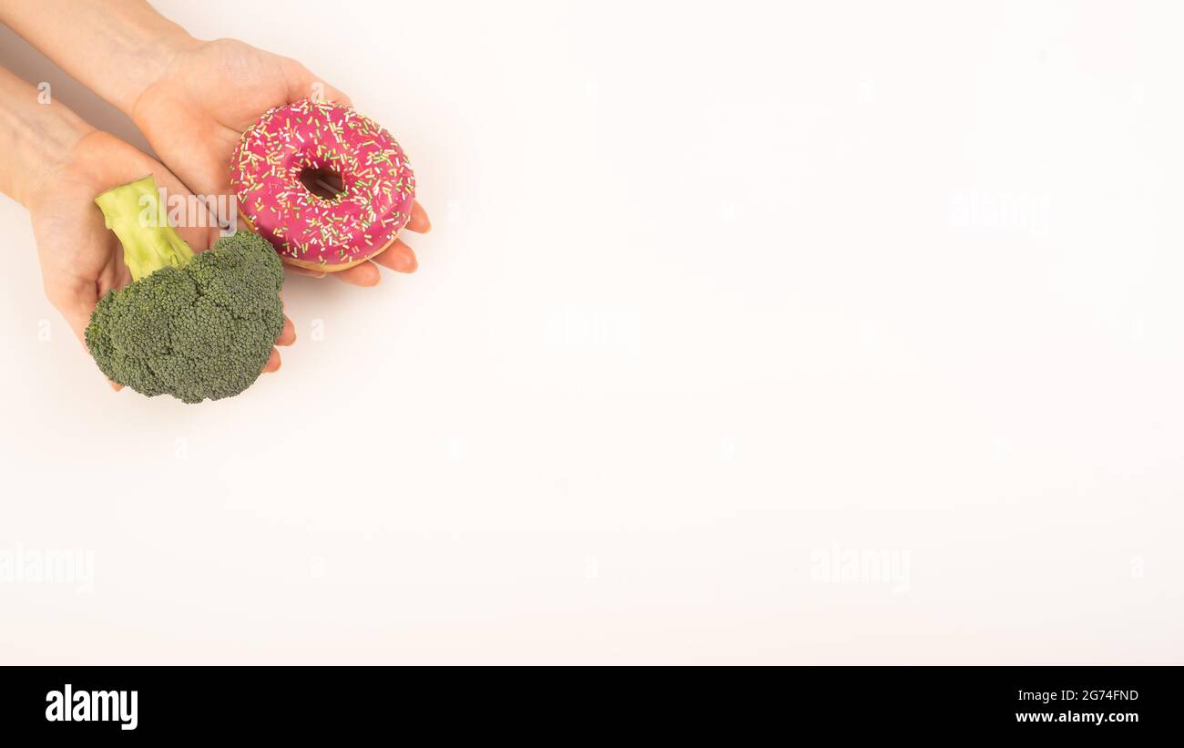 Comparison of eating habits. Woman holding broccoli and donut on a ...