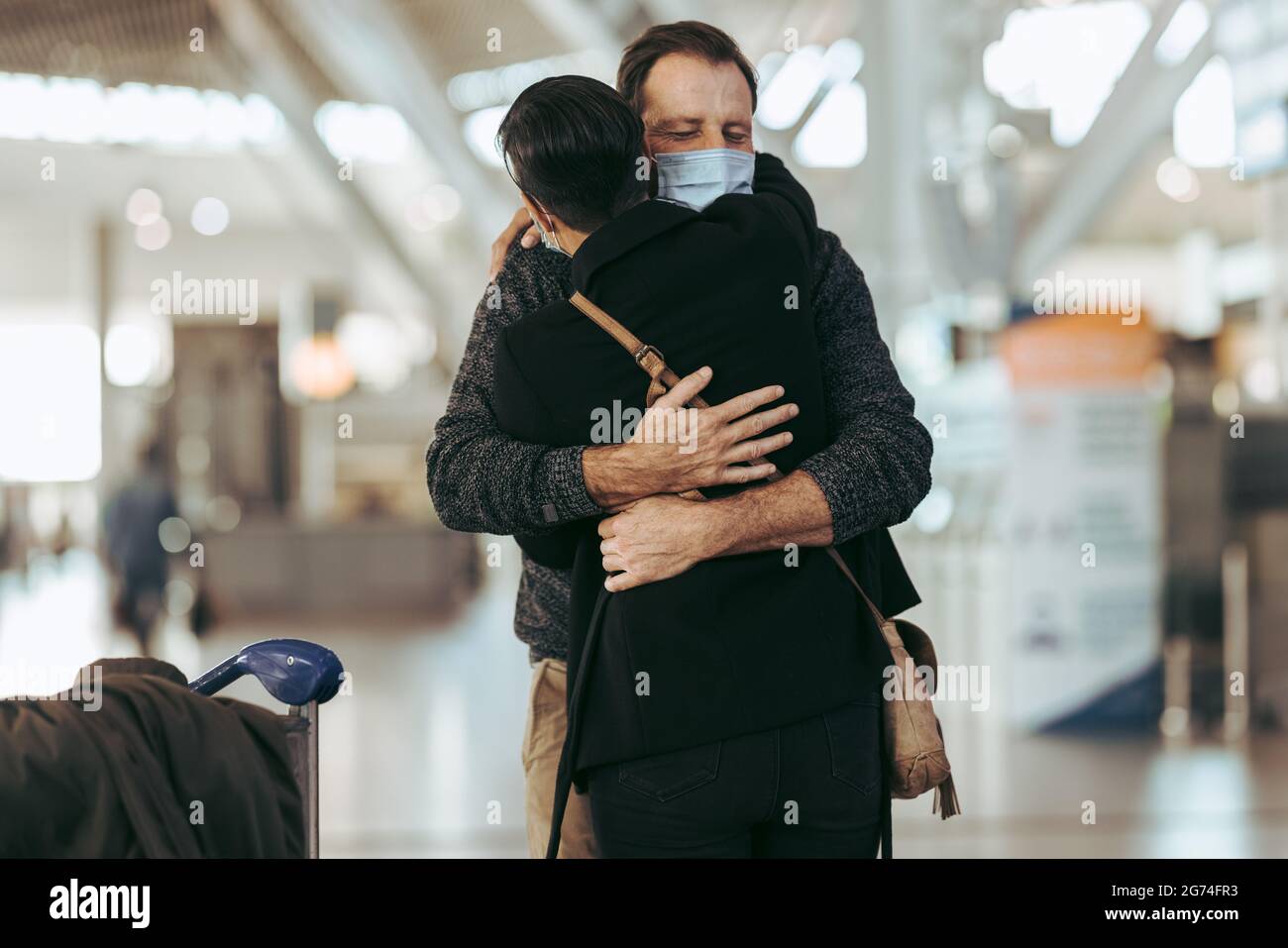 Man giving hug to woman after arrival from trip post pandemic at ...