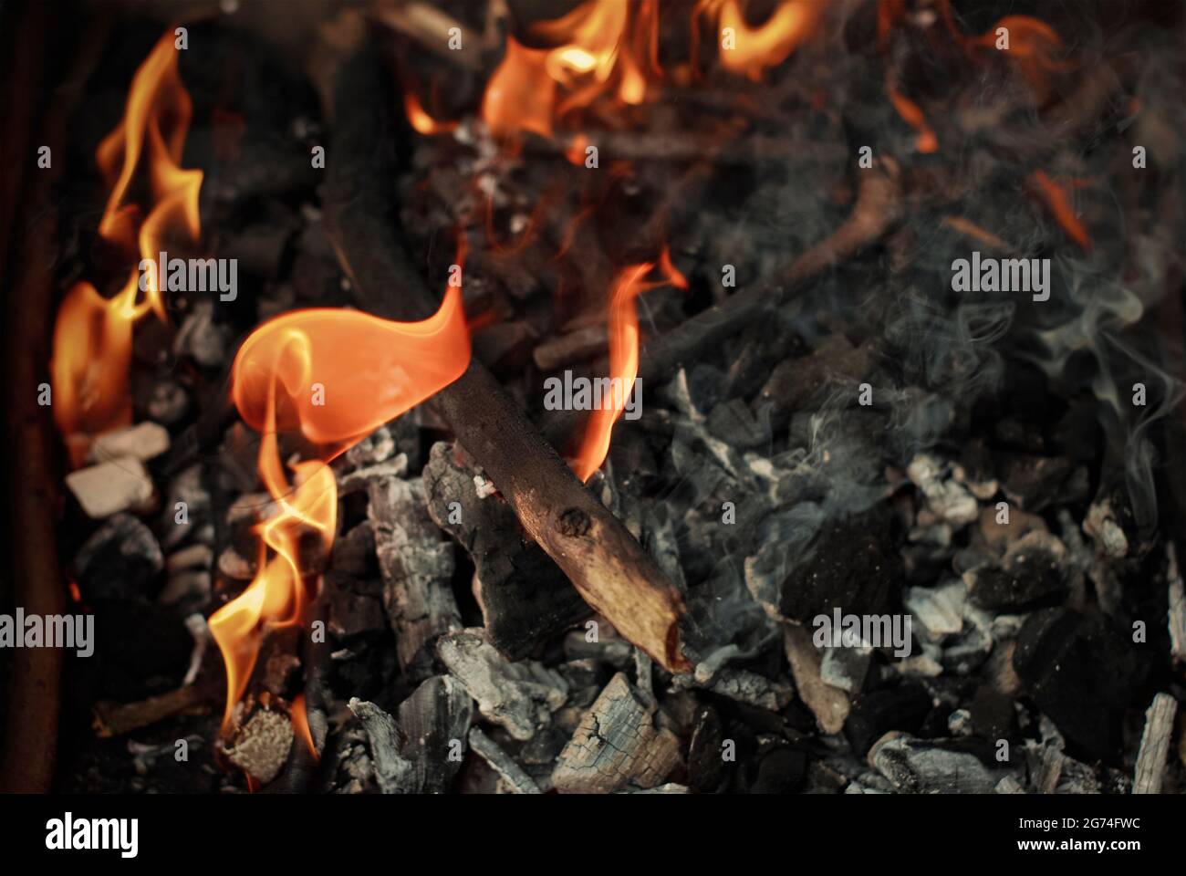 A closeup of detail of the fire and the charcoal and wood embers of a ...
