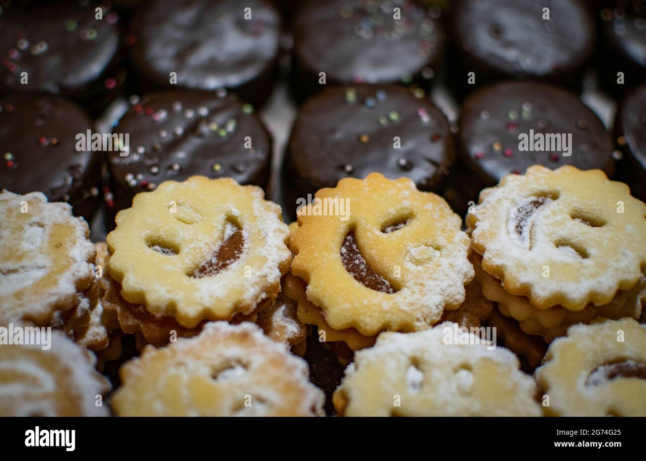 A closeup of two-layer smiling cookies with chocolate ones in parallel ...