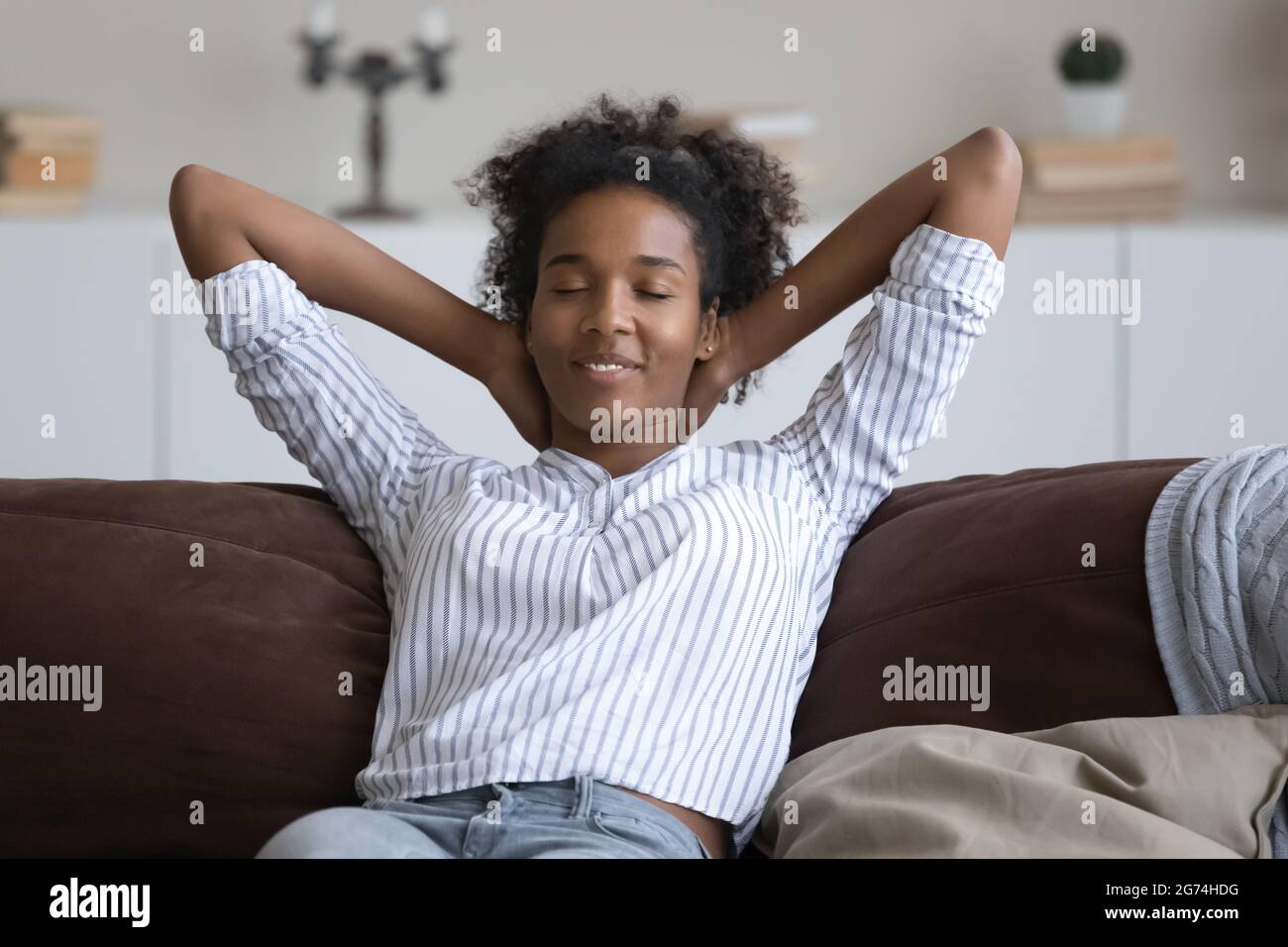 Peaceful smiling African American woman resting leaning back on couch ...