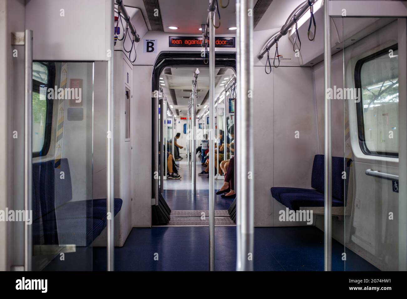 Corridor of subway cars with blue fabric seats and passengers, inside ...