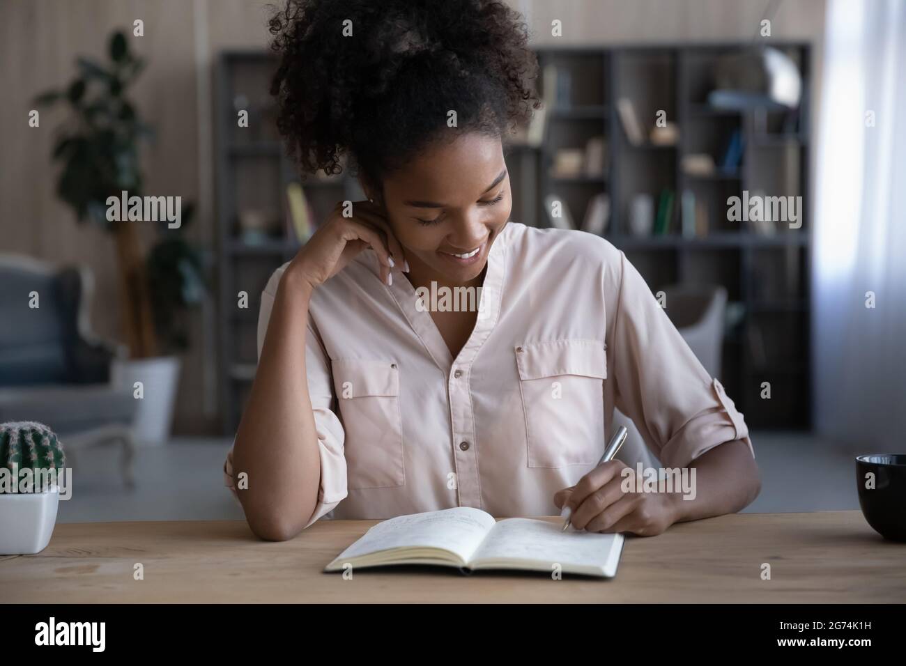 Smiling African American woman taking notes, writing in notebook Stock ...