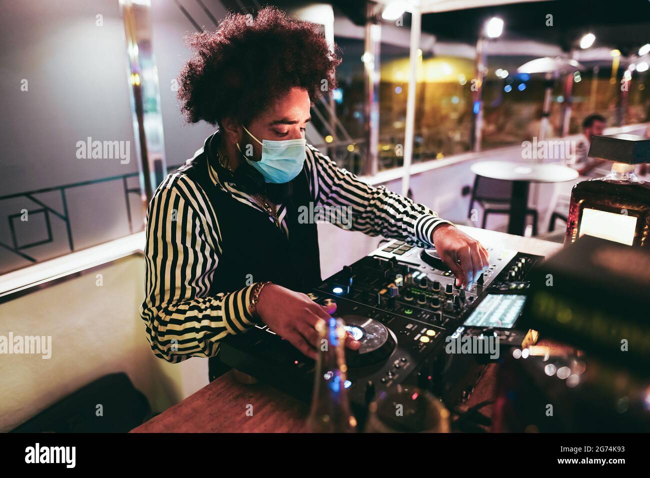 African dj playing music at cocktail bar outdoor while wearing face ...
