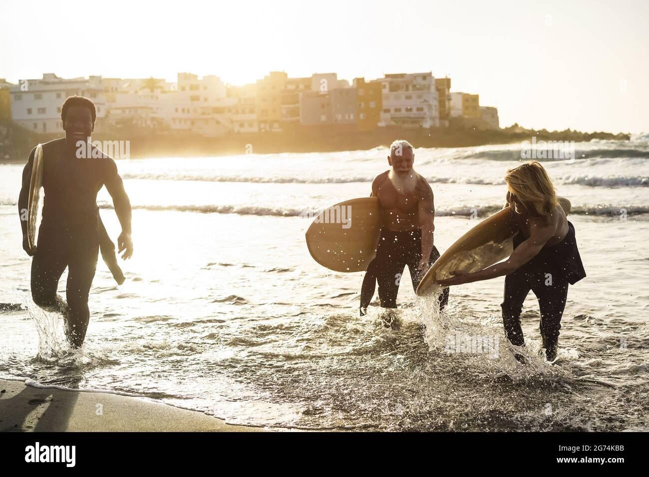 Multi generational surfer friends having fun while surfing on beach ...