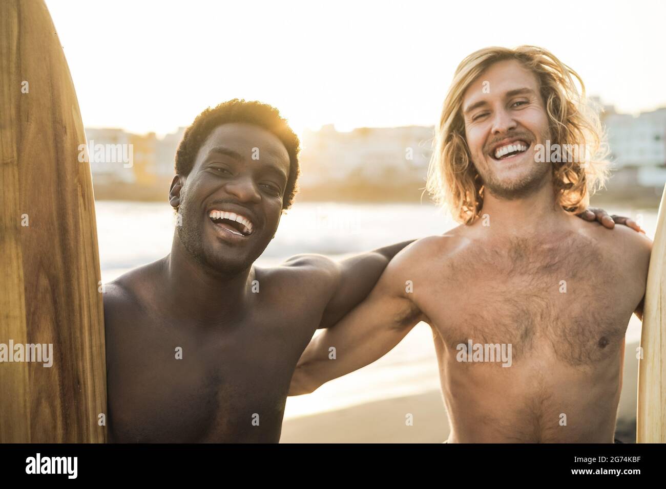 Happy multiracial surfers having fun on the beach after surf session ...