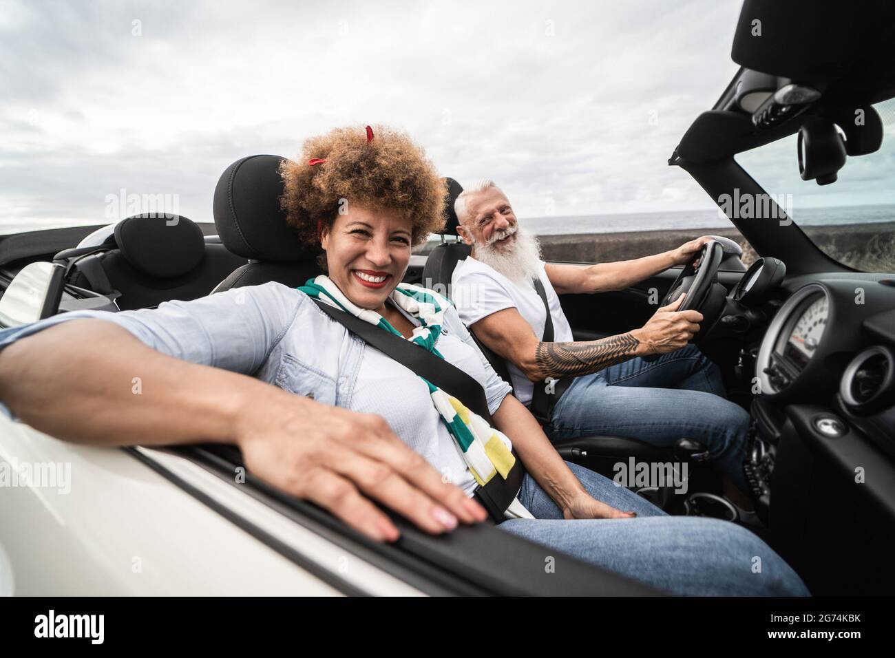 Trendy senior couple having fun in convertible car during summer ...